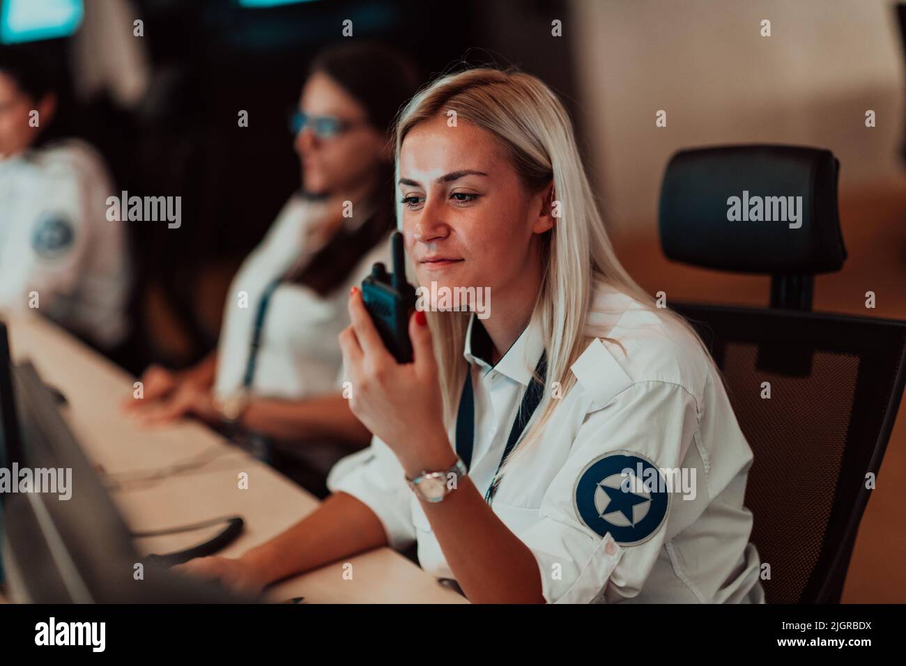 Female security operator holding portable radio in hand while working ...