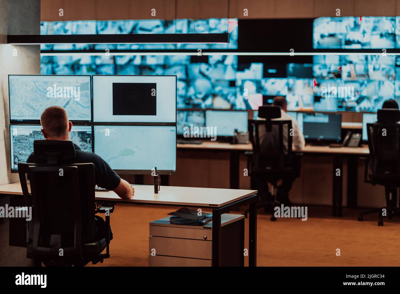 Male security operator working in a data system control room offices ...