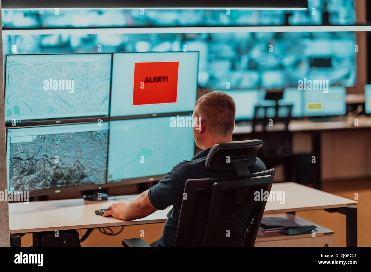 Male security operator working in a data system control room offices ...
