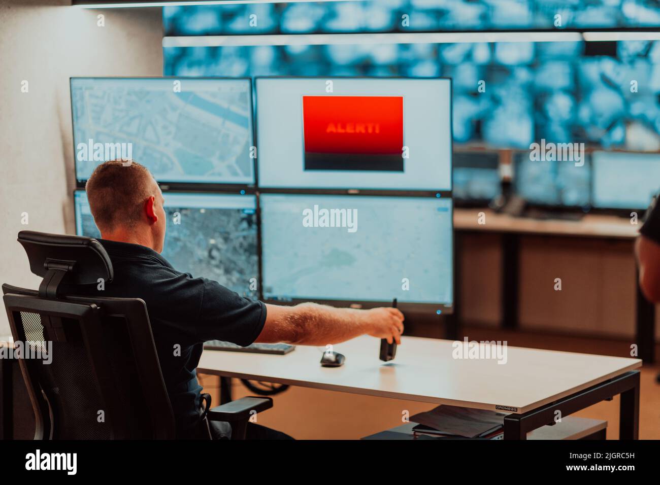Male security operator working in a data system control room offices ...