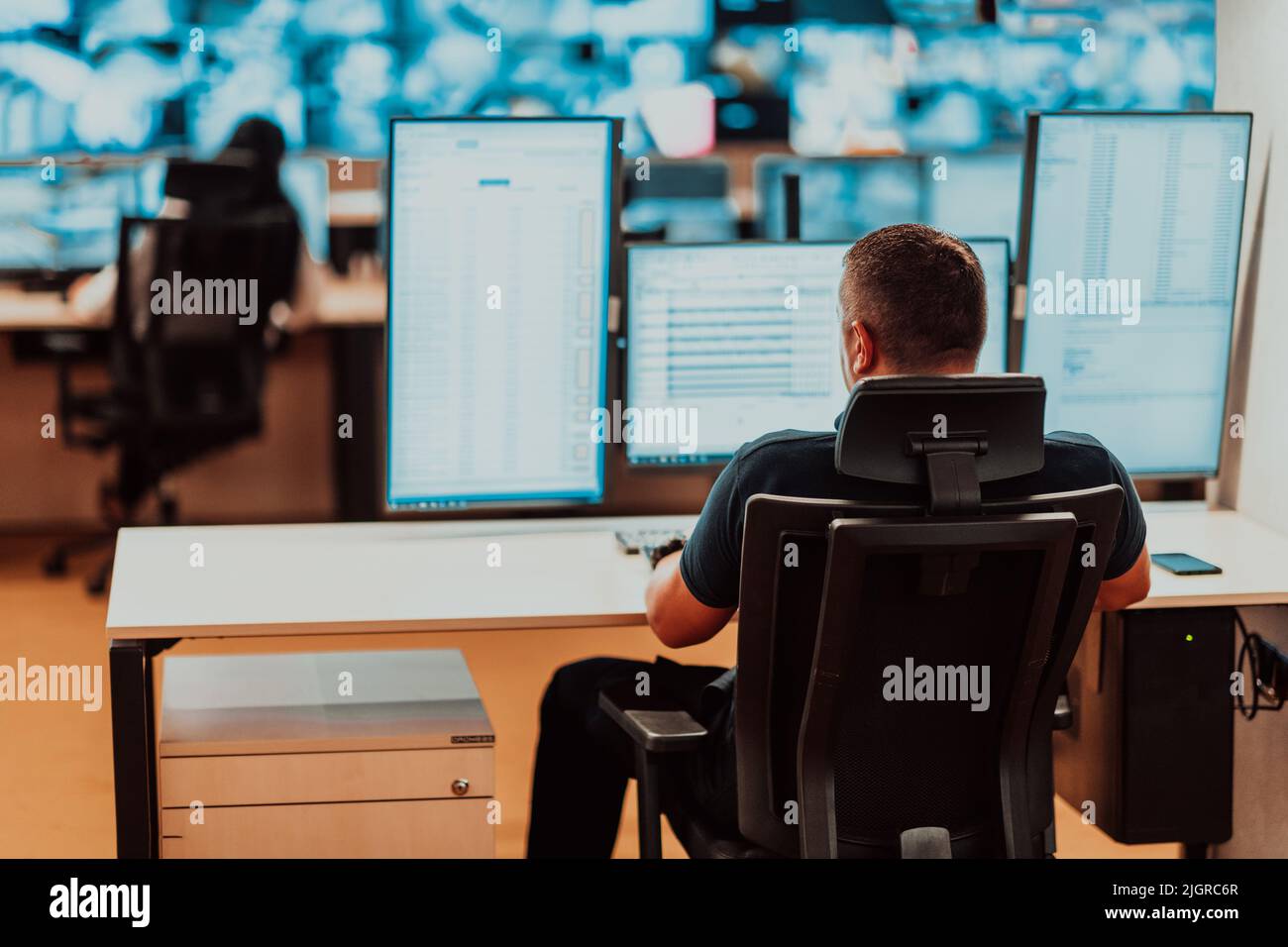 Male security operator working in a data system control room offices ...
