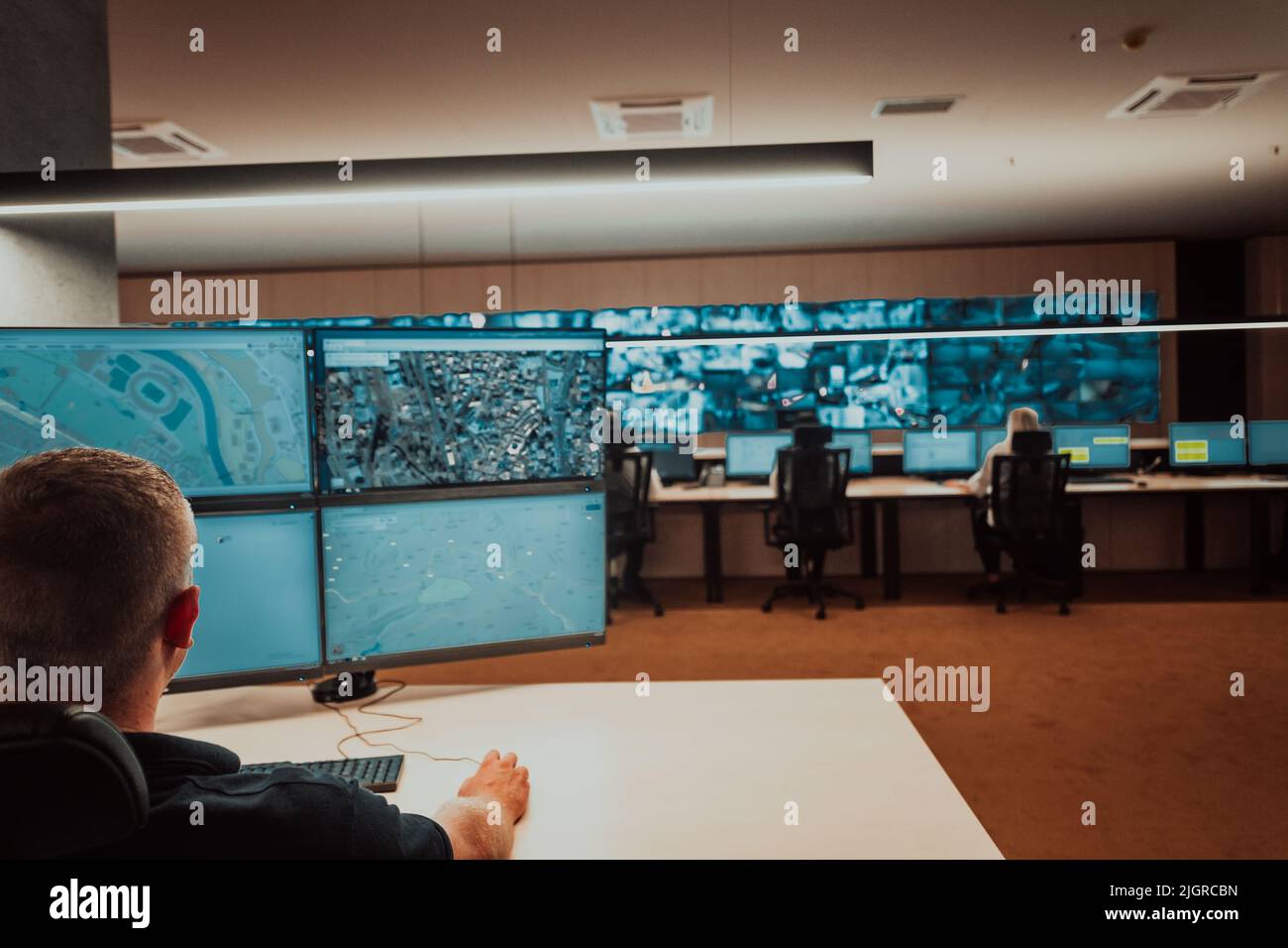 Male security operator working in a data system control room offices ...