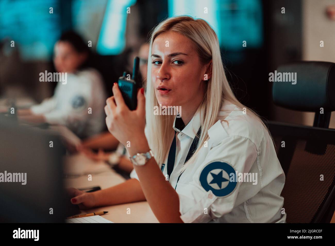Female security operator holding portable radio in hand while working ...