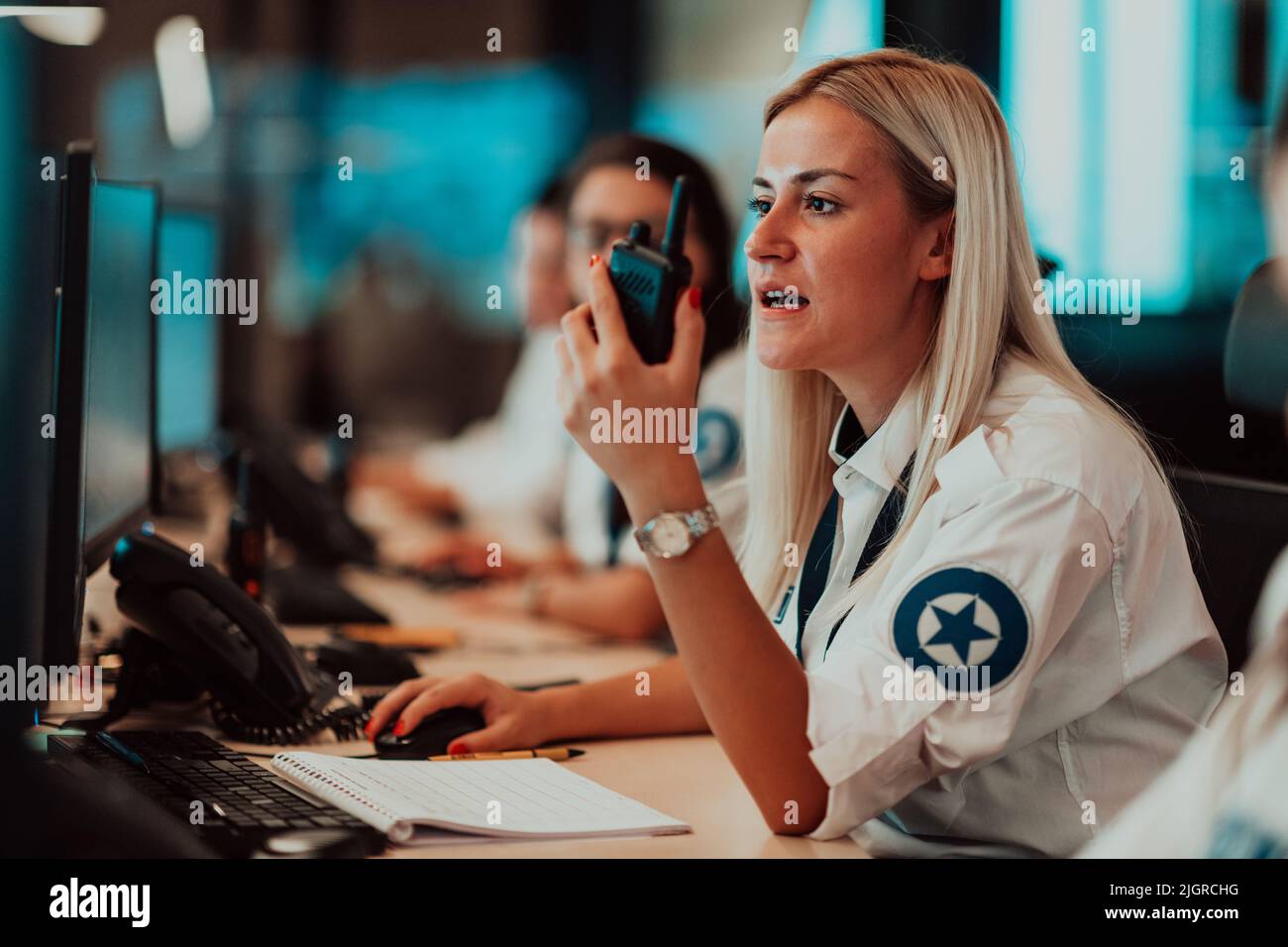 Female security operator holding portable radio in hand while working ...