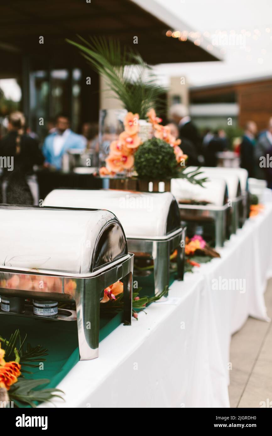 A vertical shot of a buffet table with food in chafing dishes and ...