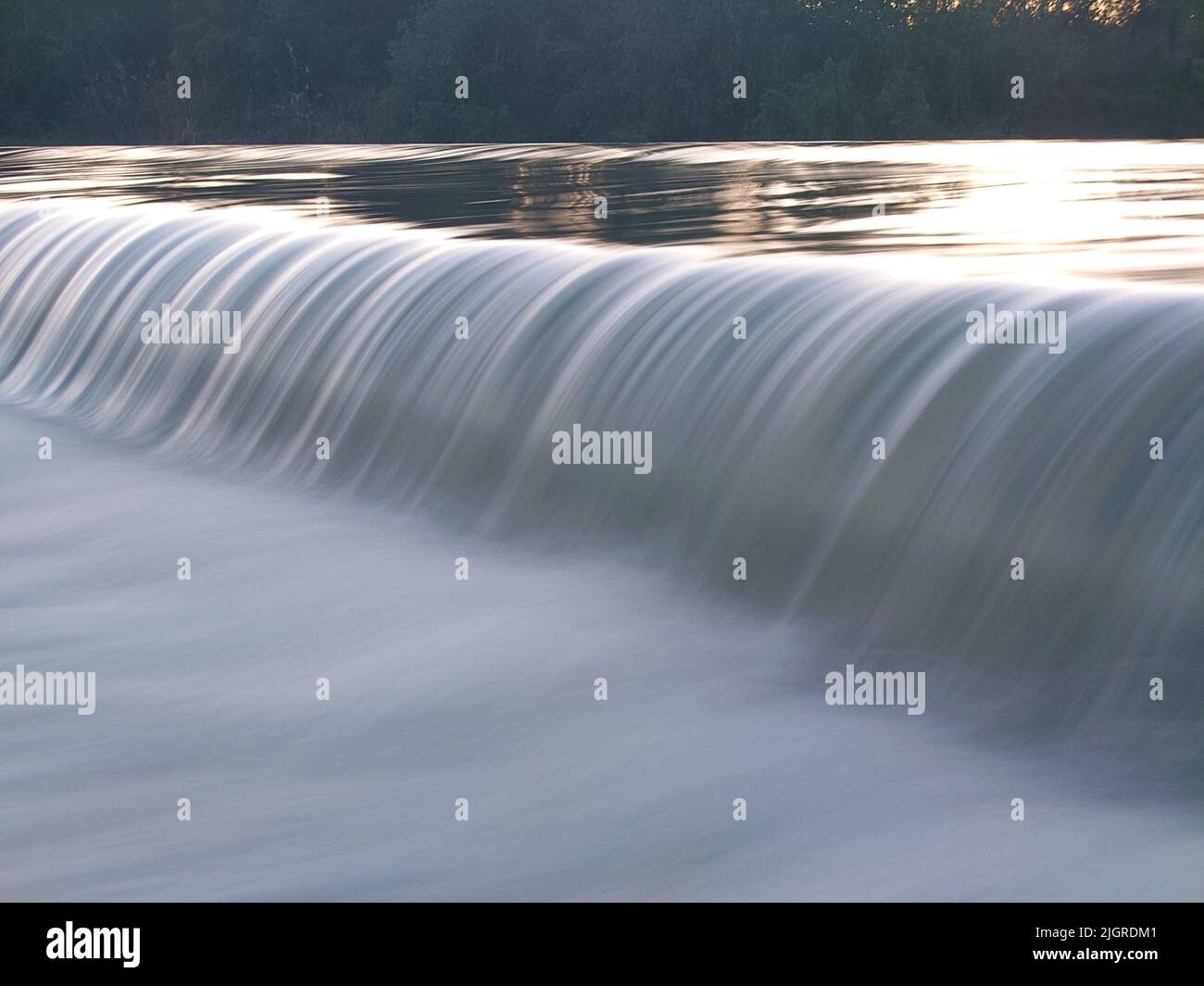 The foaming water flowing over a small dam in long exposure Stock Photo ...