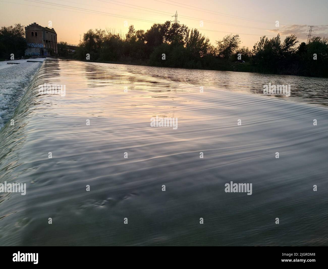 The foaming water flowing over a small dam Stock Photo - Alamy