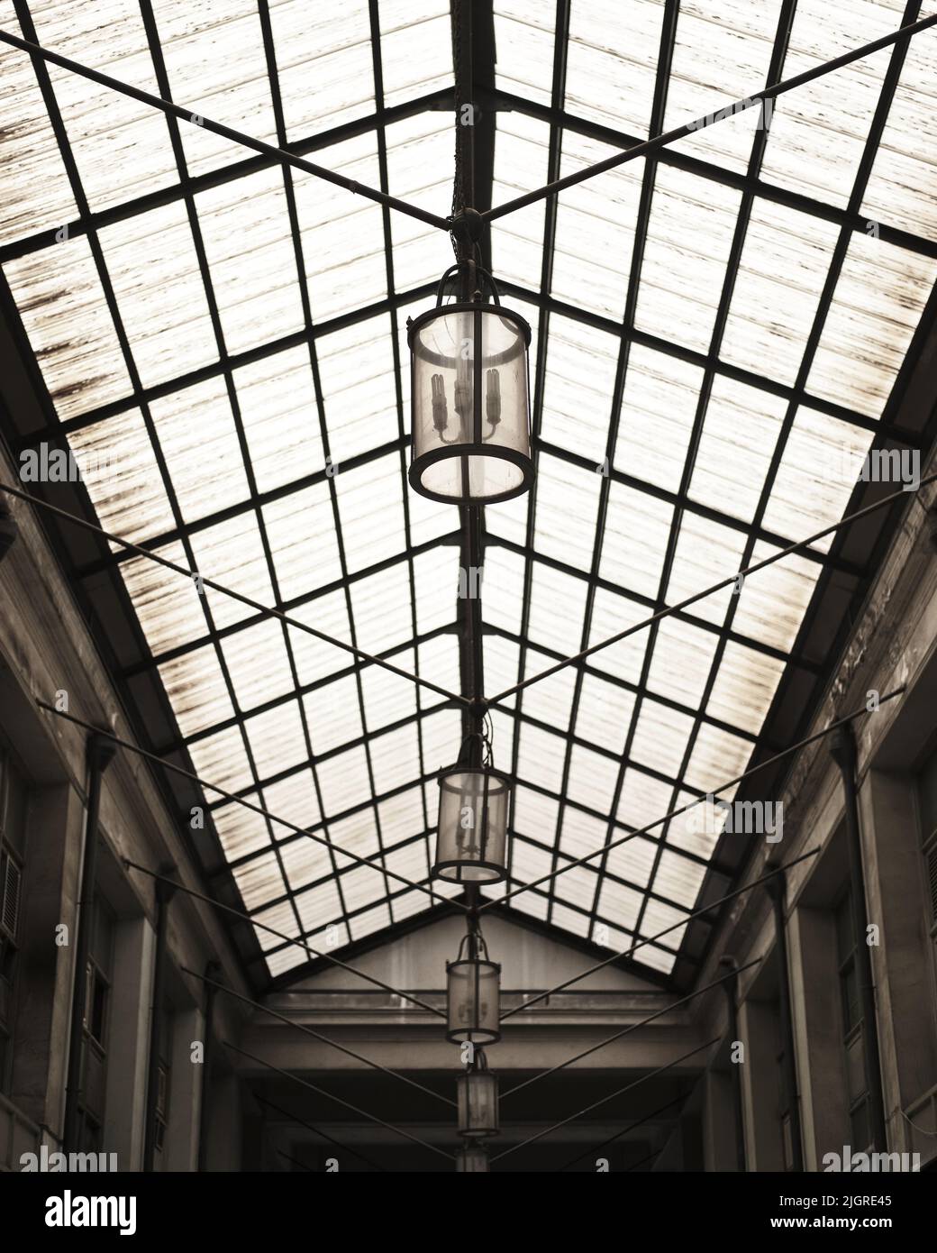 A vertical shot of hanging cylinder antique lighting on a glass ceiling ...