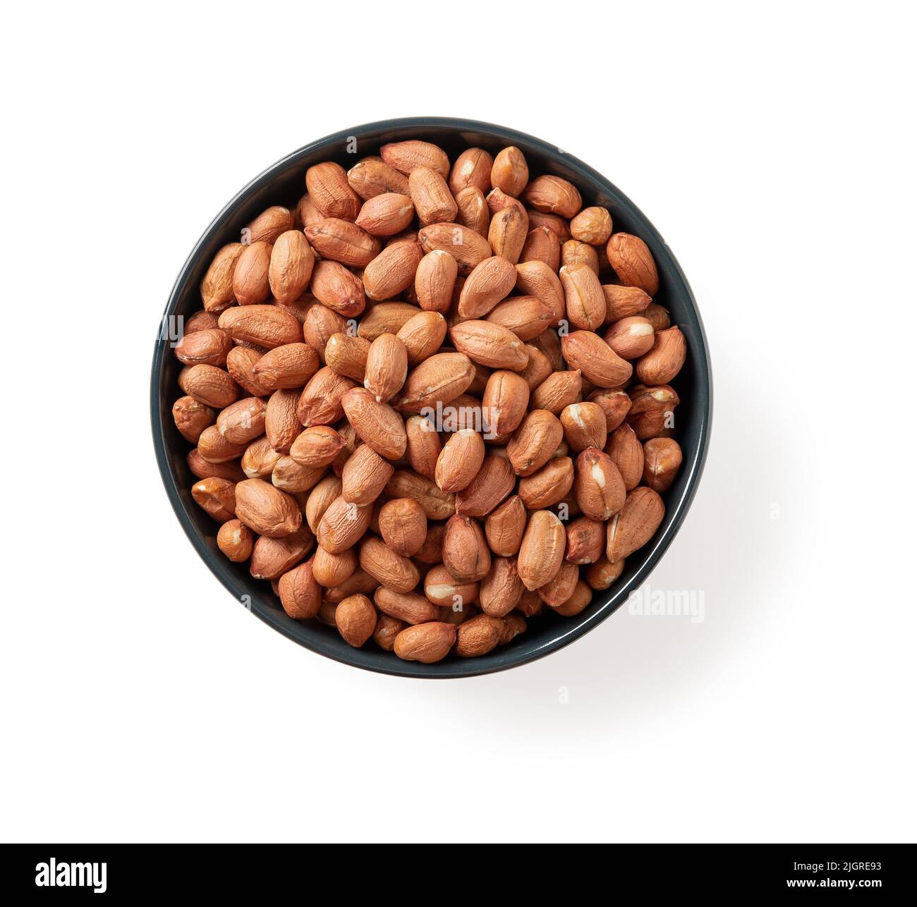 Dried oranic peanut seeds in a blue bowl isolated on a white background ...