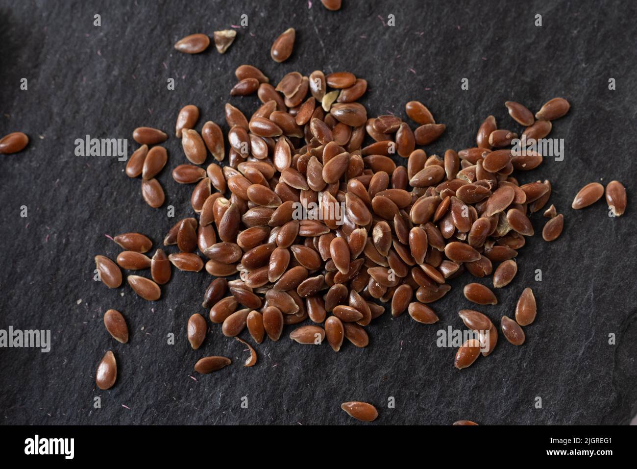Flax seeds on a black background. Lion scattered on a tray. View from ...