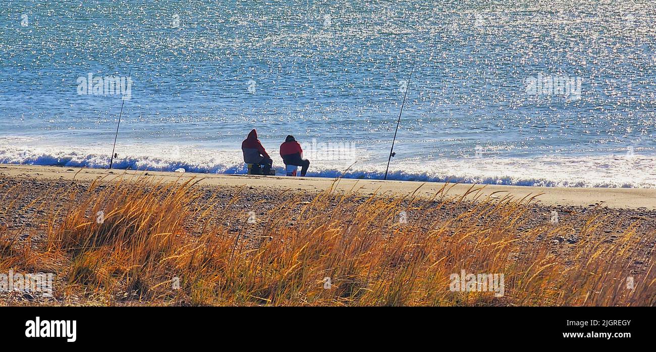 A view of two fishers sitting on the sandy beach Stock Photo - Alamy