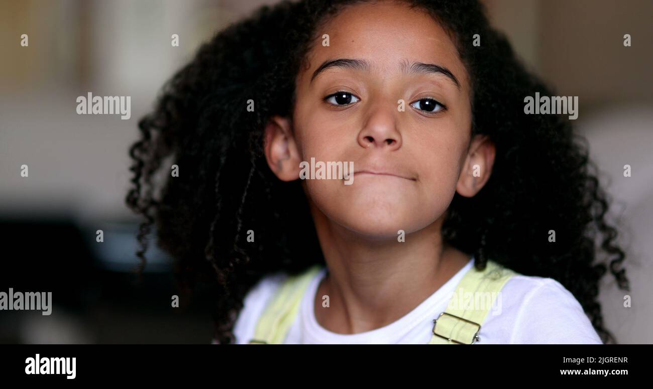 Bored Mixed race little girl pressing lips staring camera Stock Photo ...