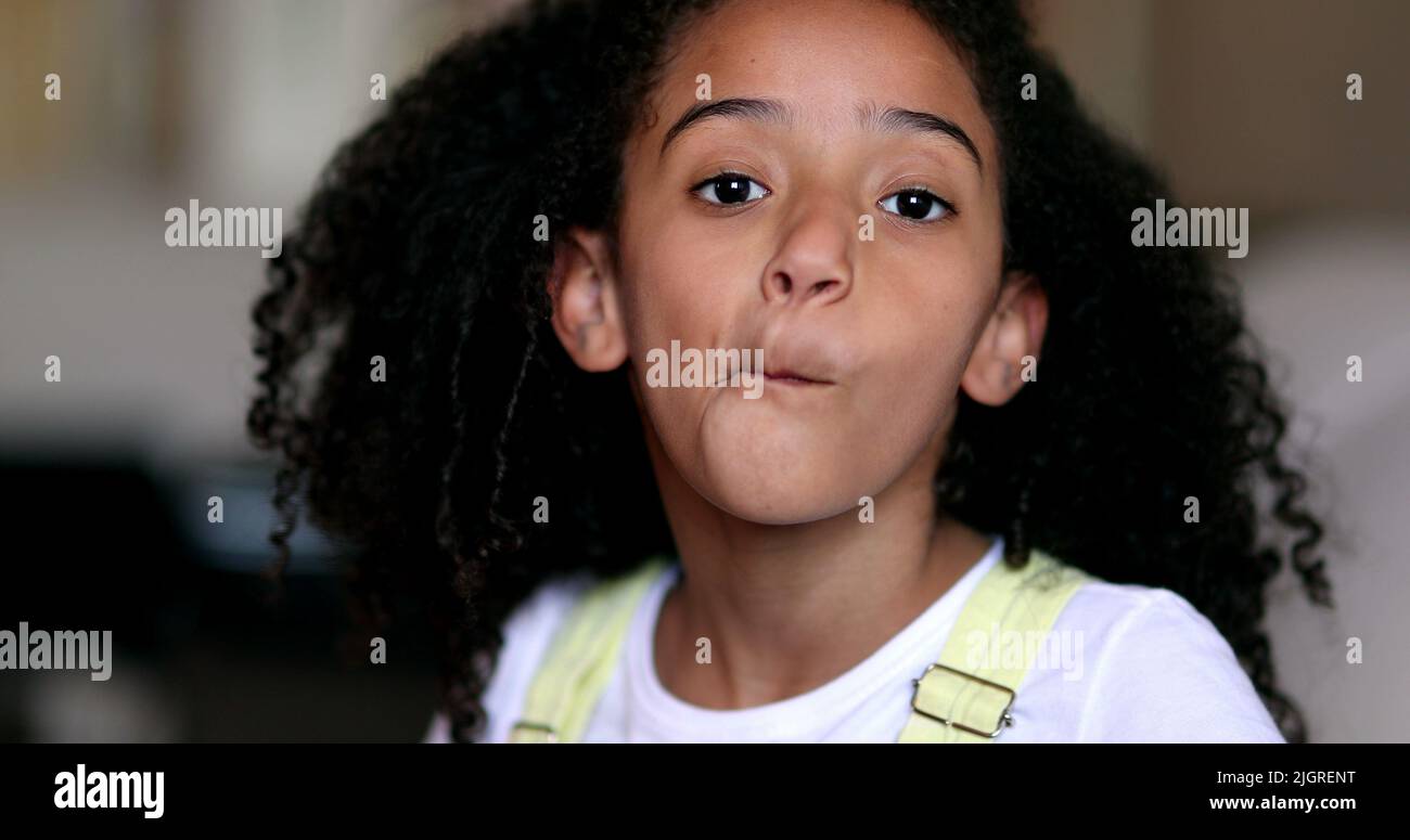 Bored Mixed race little girl pressing lips staring camera Stock Photo ...