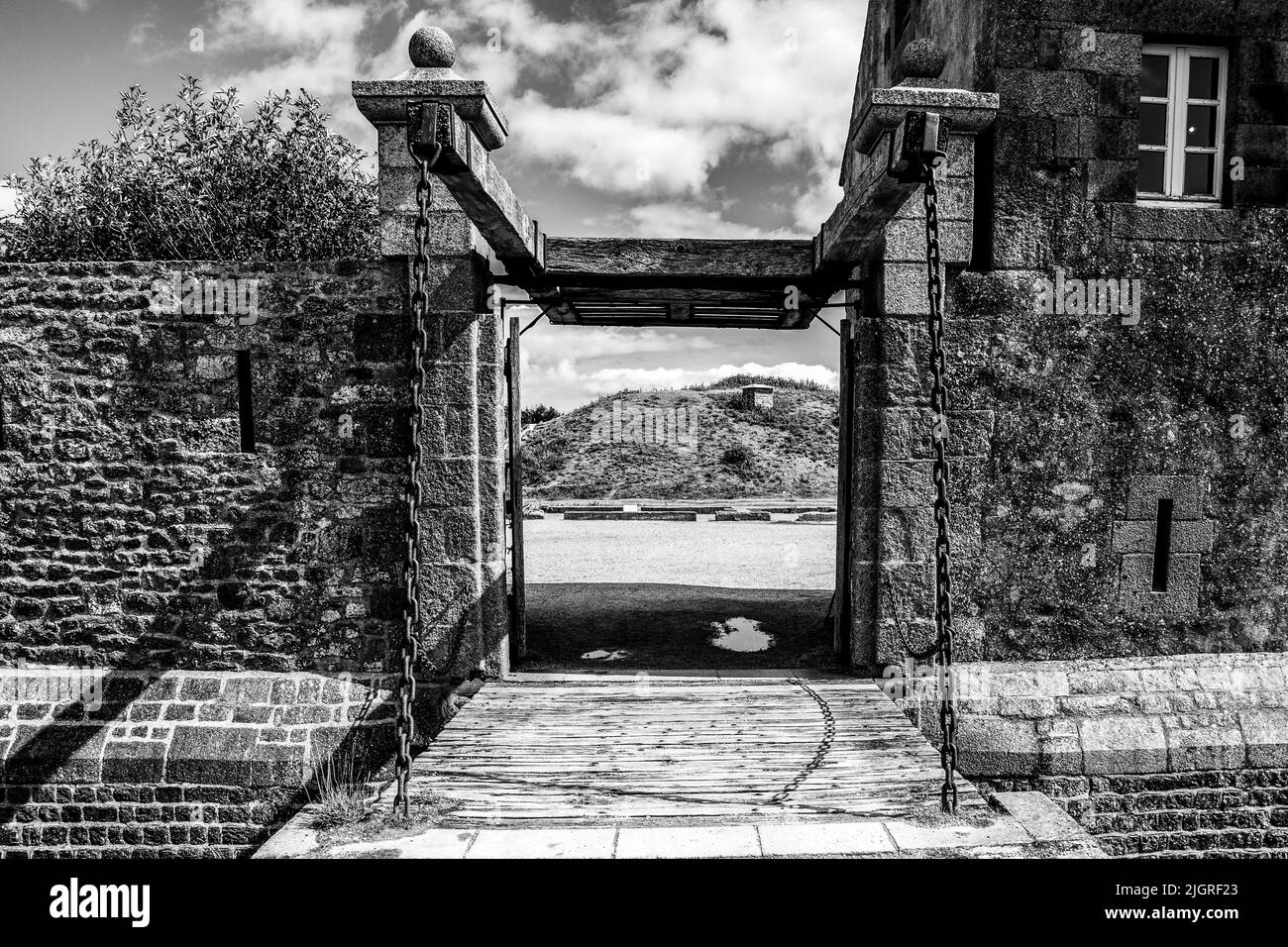 A grayscale shot of a walkway leading to a gate chained to the ground ...