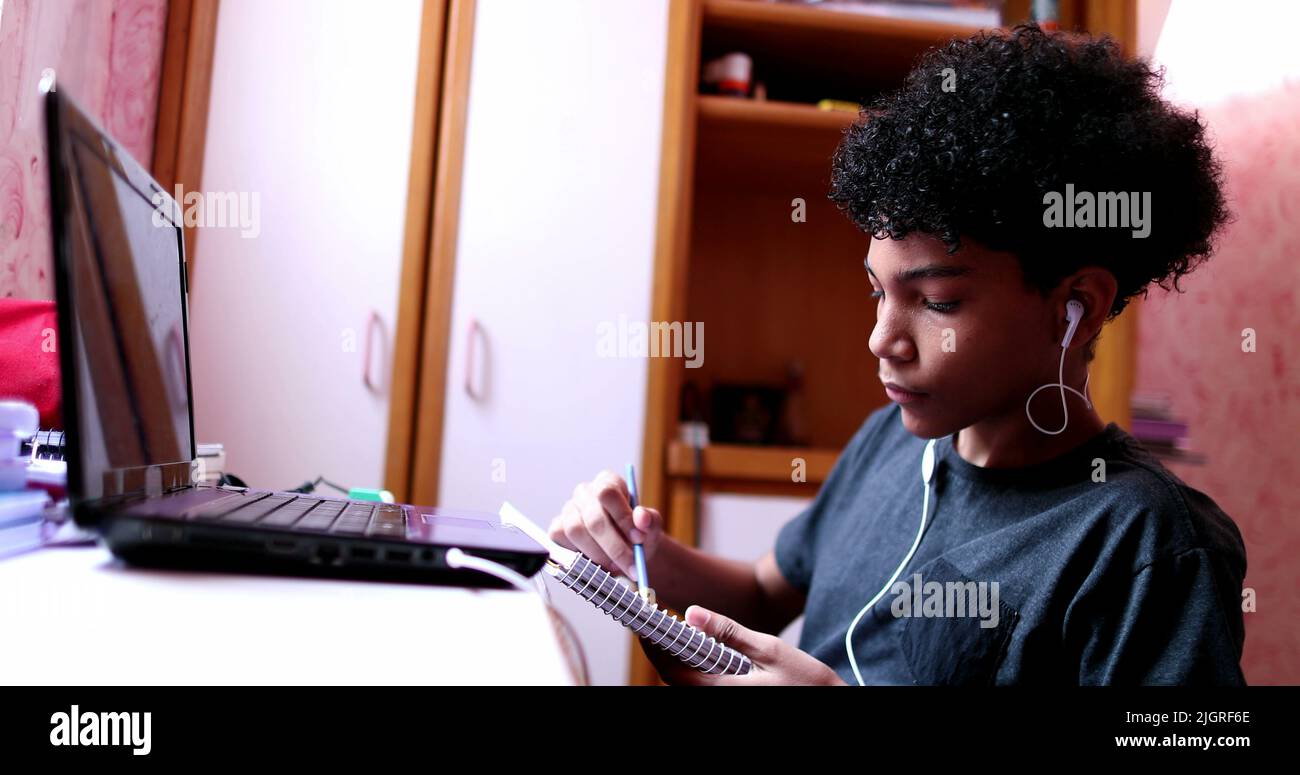 Child doing homework at home in front of laptop. Black ethnicity kid ...