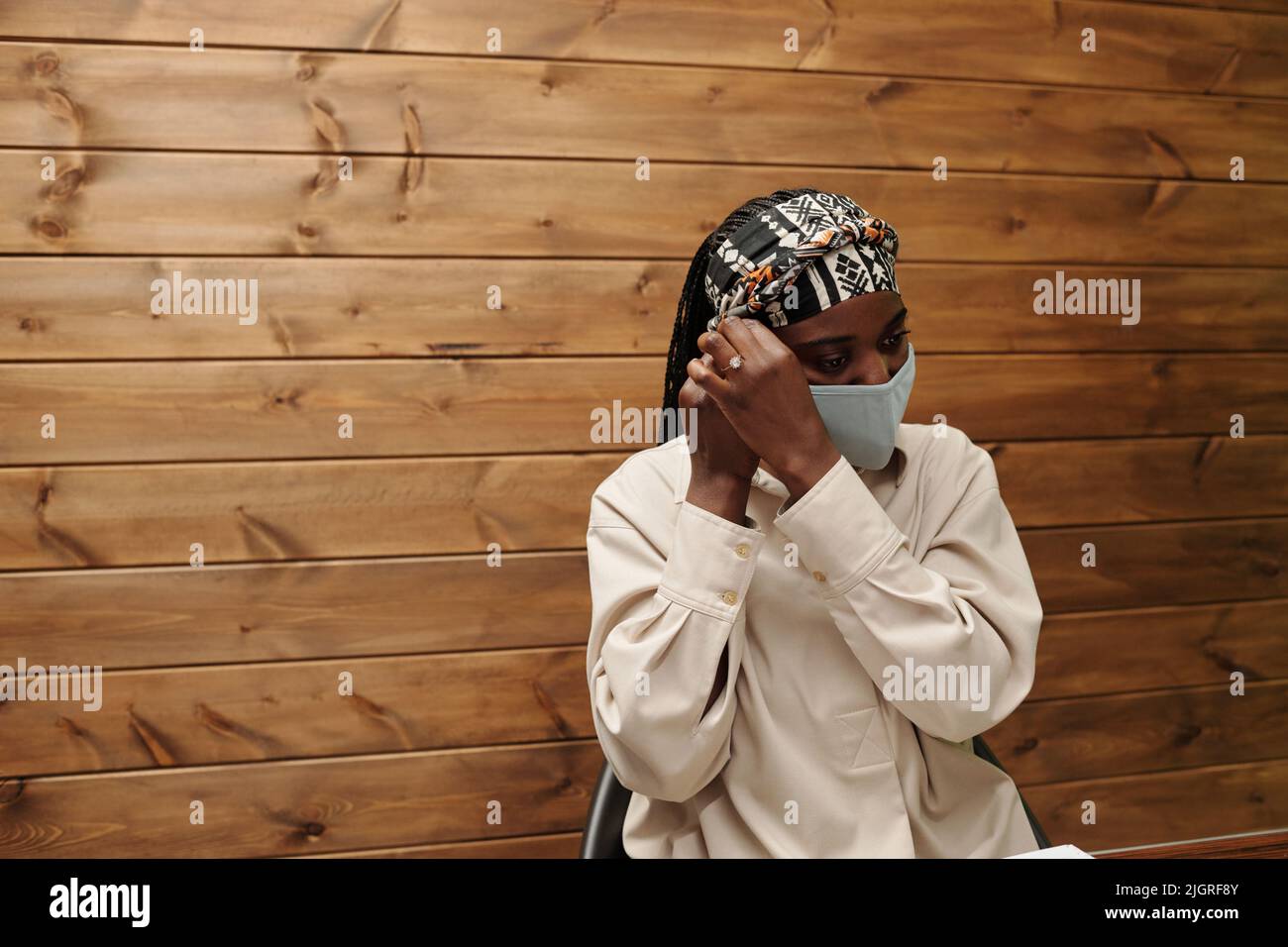 Young African American businesswoman putting on protective face mask to ...