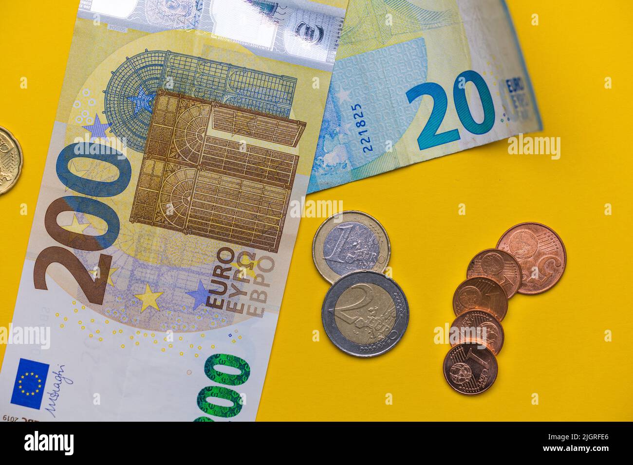 Euro banknotes and coins on yellow background. 1 Cent, 2 Cent, 20 Euro ...