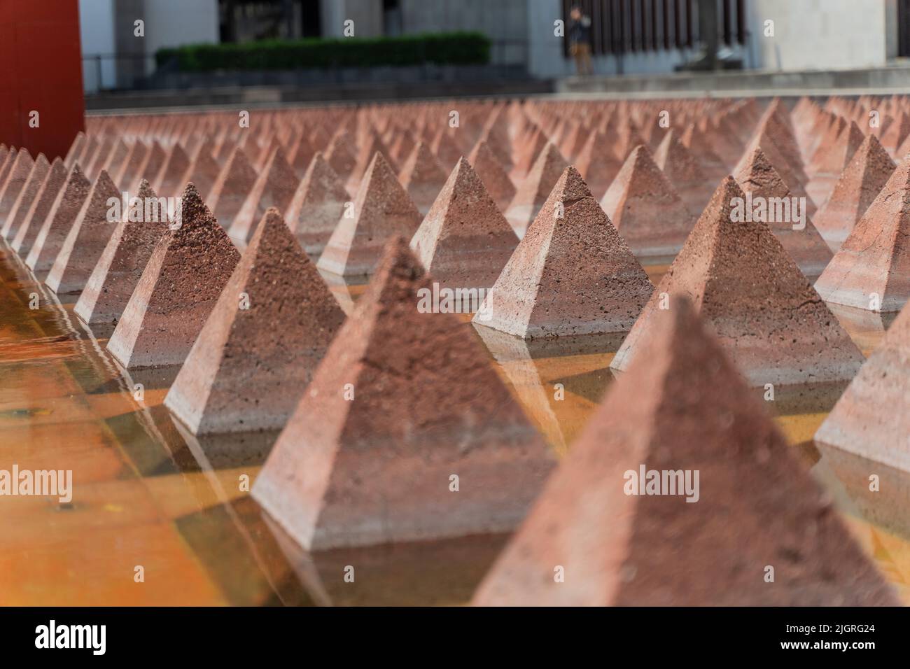Small burnt red concrete pyramids reflected in the water in the Memory ...