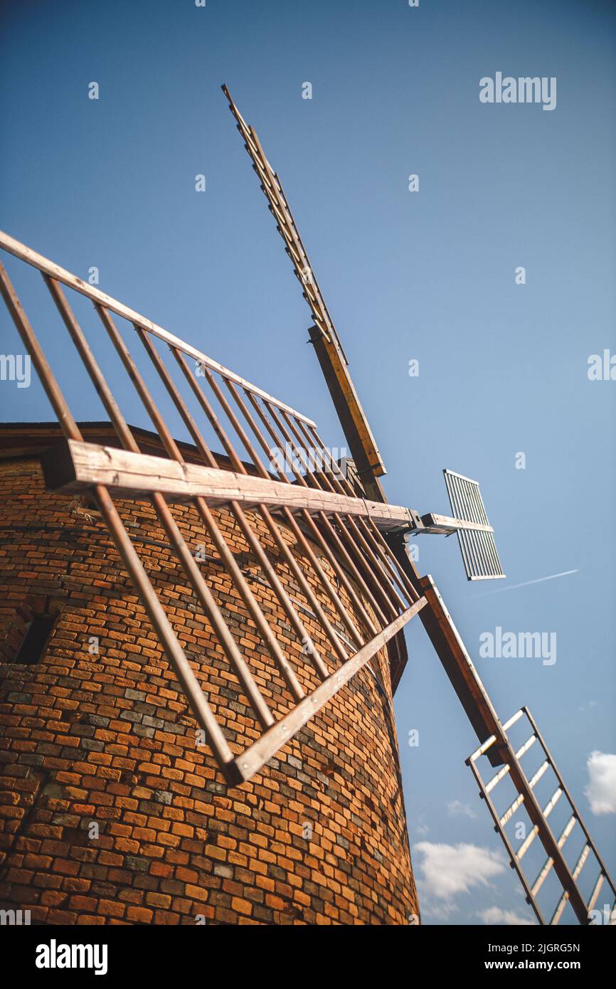 A vertical low angle shot of an old brick windmill in the fields of ...