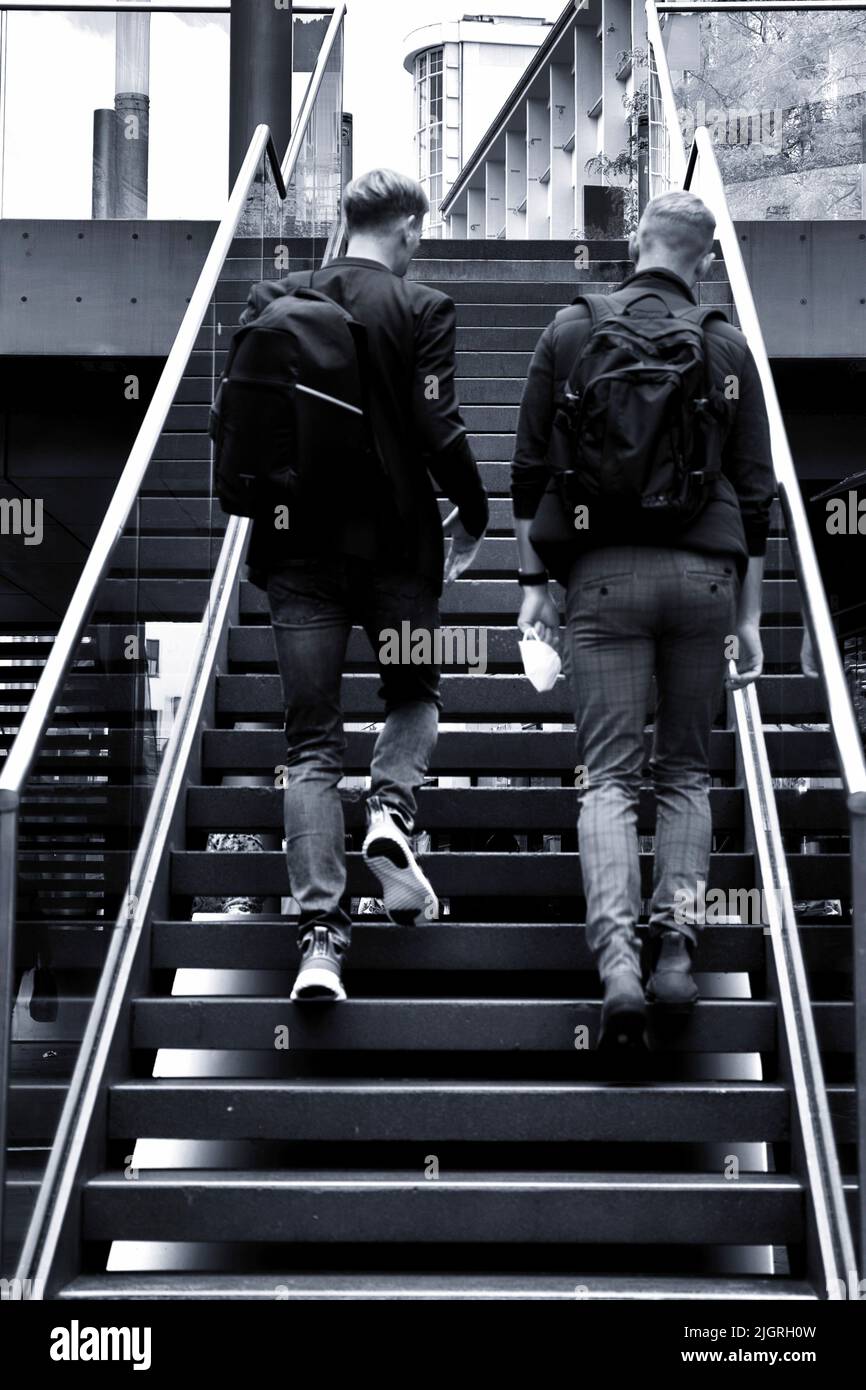 A vertical shot of two men going up the stairs towards a building in ...