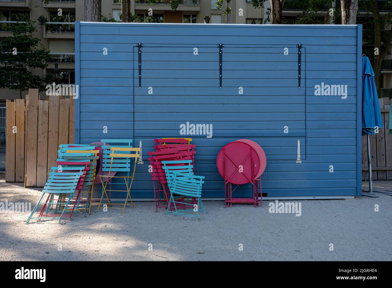 A closed blue wooden cabin with colorful closed chairs, tables and ...