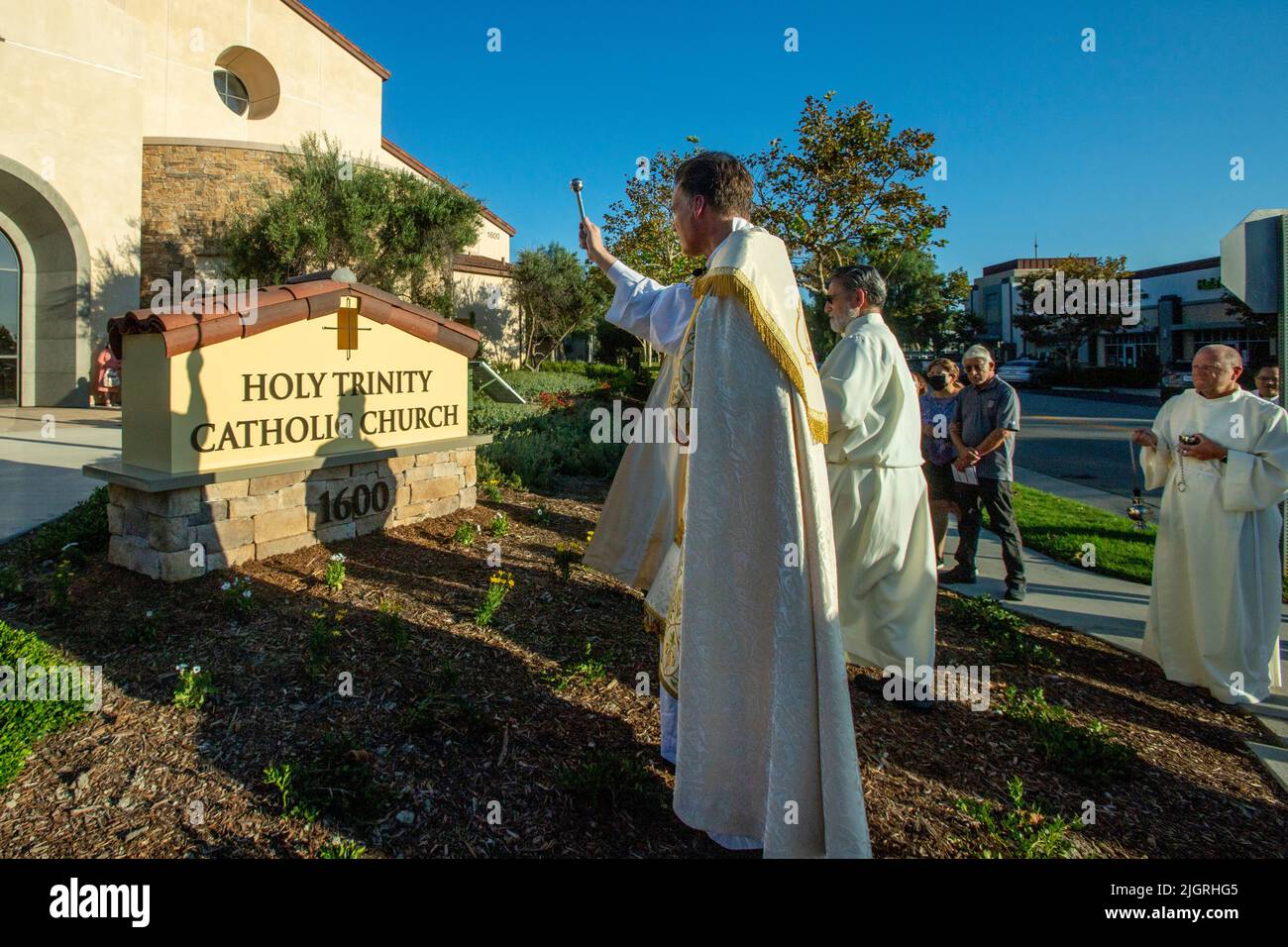Using an aspergillum, a priest sprinkles holy water on the sign in the ...