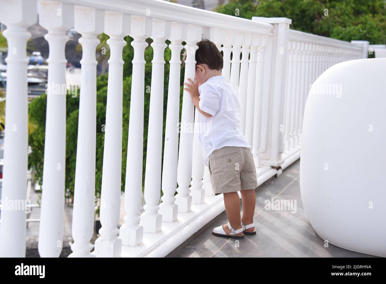 A beautiful baby boy looking out of a balcony in daylight Stock Photo ...