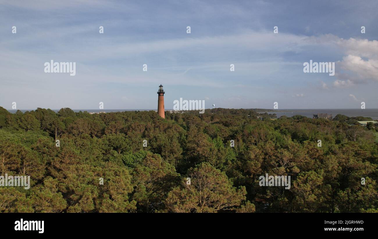 The Currituck Beach Lighthouse surrounded by lush green trees in ...