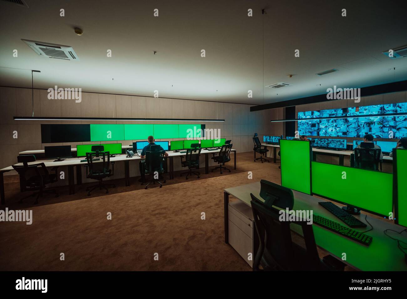 Male security operator working in a data system control room offices ...