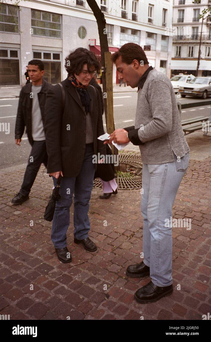 A pedestrian asks directions of a woman passerby on a street in Paris ...