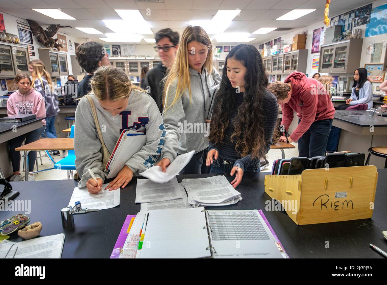 High school chemistry students turn in their homework papers at the ...