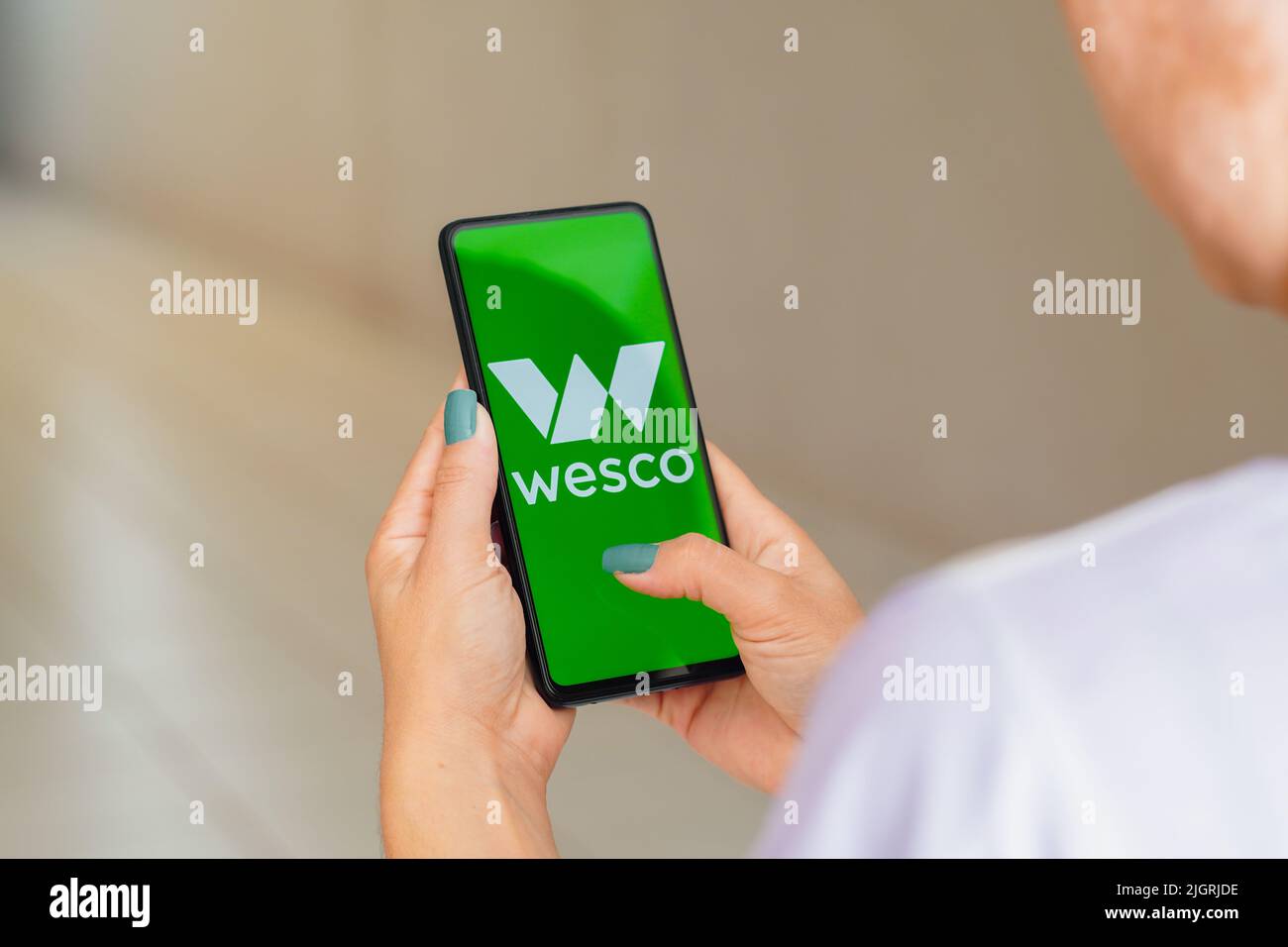 In this photo illustration, a woman holds a smartphone with the WESCO ...