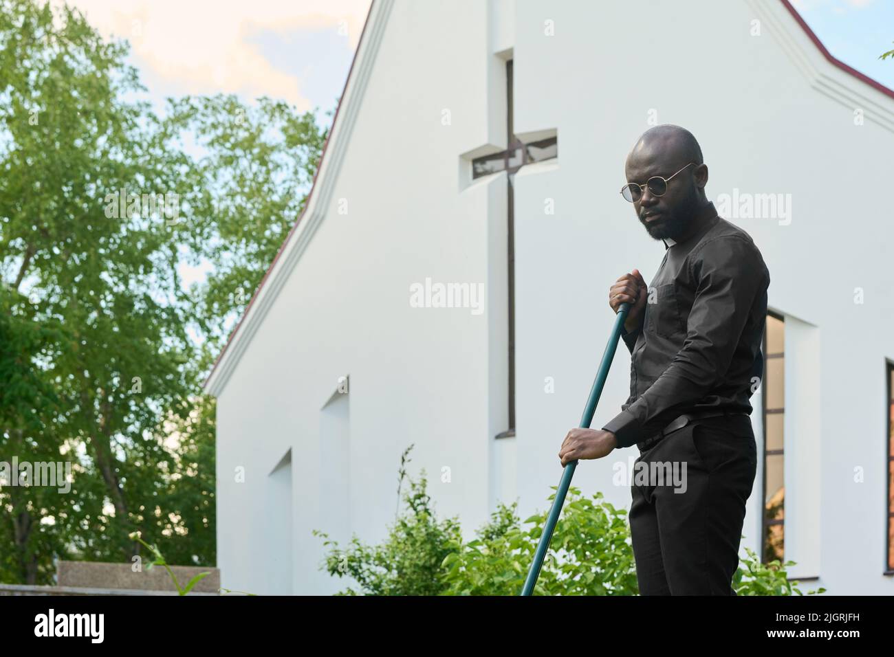 Young serious African American pastor in black pants and shirt and ...