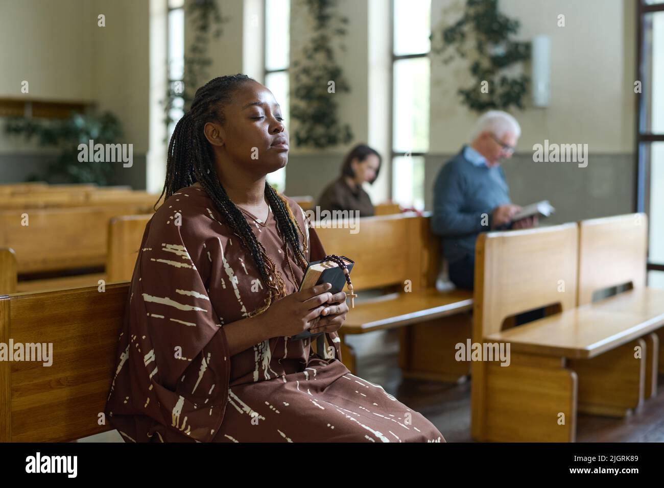 Young Christian black woman in casual dress kkeeping her eyes closed ...