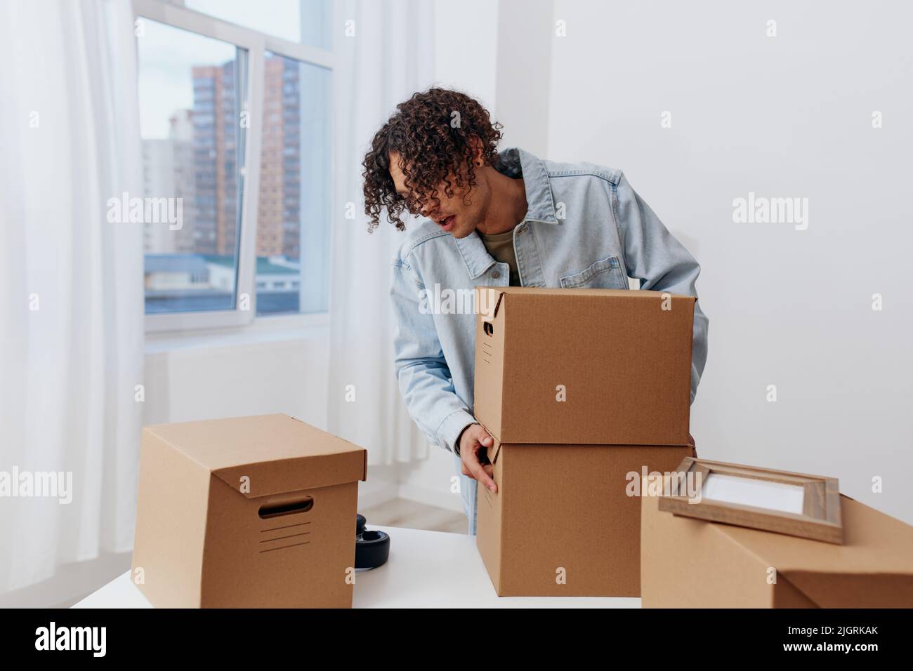 A young man unpacking things from boxes in the room interior Stock ...