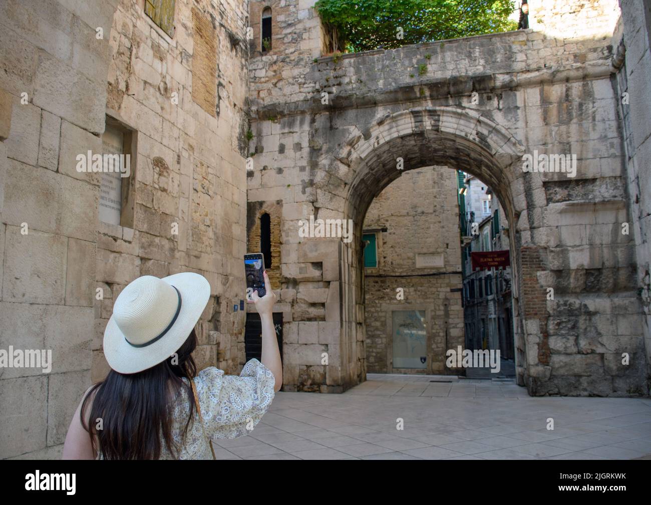 A young woman taking photos of the golden gates of Diocletian's Palace ...