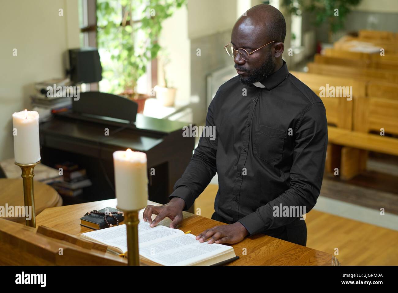 Young serious African American pastor in black shirt with clerical ...