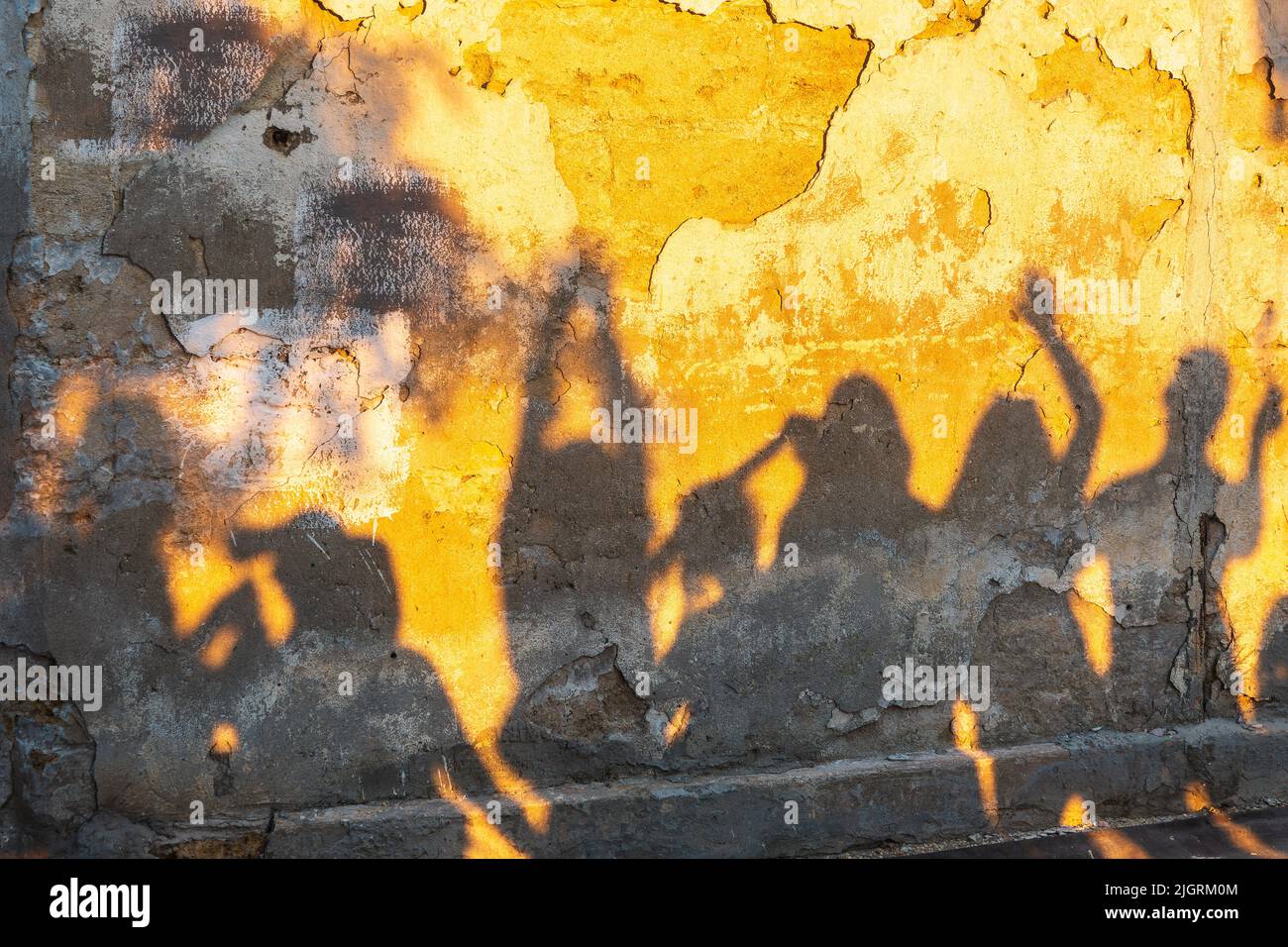 Shadows of dancing people on an old wall at sunset time. Group of human ...