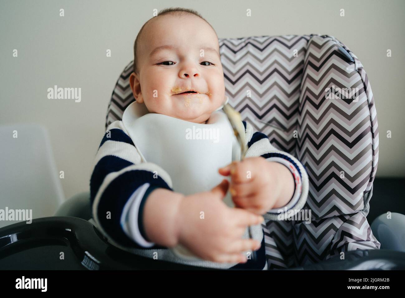 A closeup of a cute baby boy with a dirty mouth wearing a bib and ...