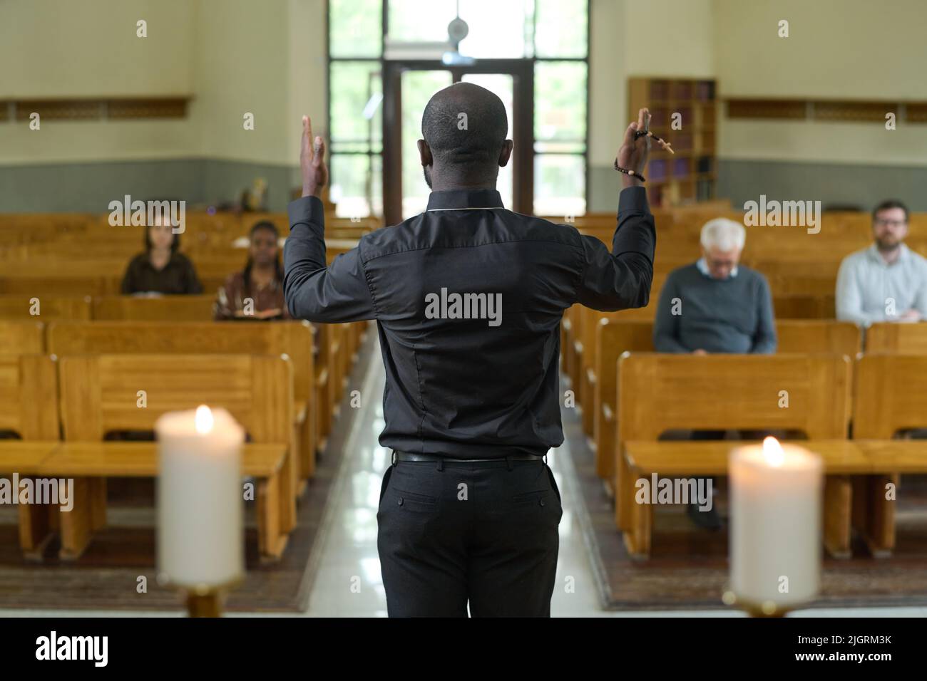 Rear view of young African American priest in black shirt and pants ...