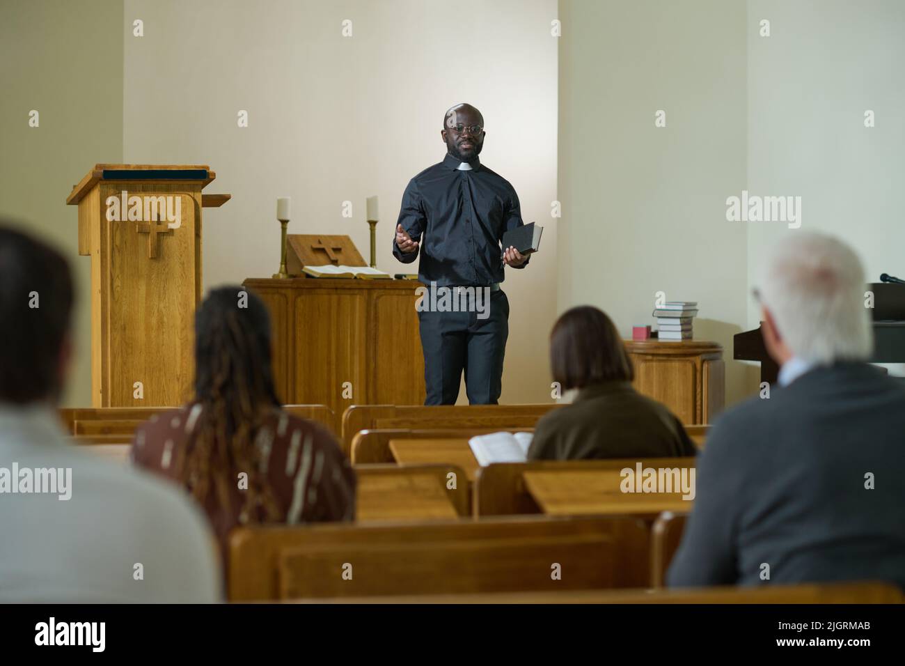 Confident priest of evangelical church with Holy Bible in hand saying ...
