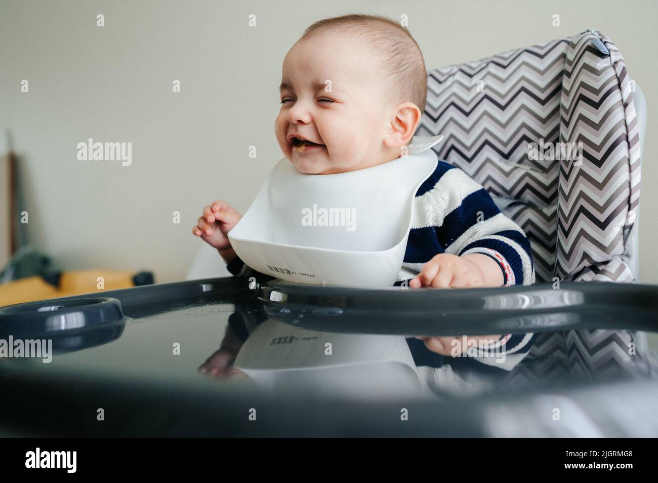 A closeup of a smiling baby boy with a dirty mouth wearing a plastic ...