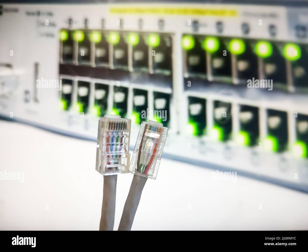 RJ45 cable tops in front of a switchboard. RJ45 Pins are used in a ...