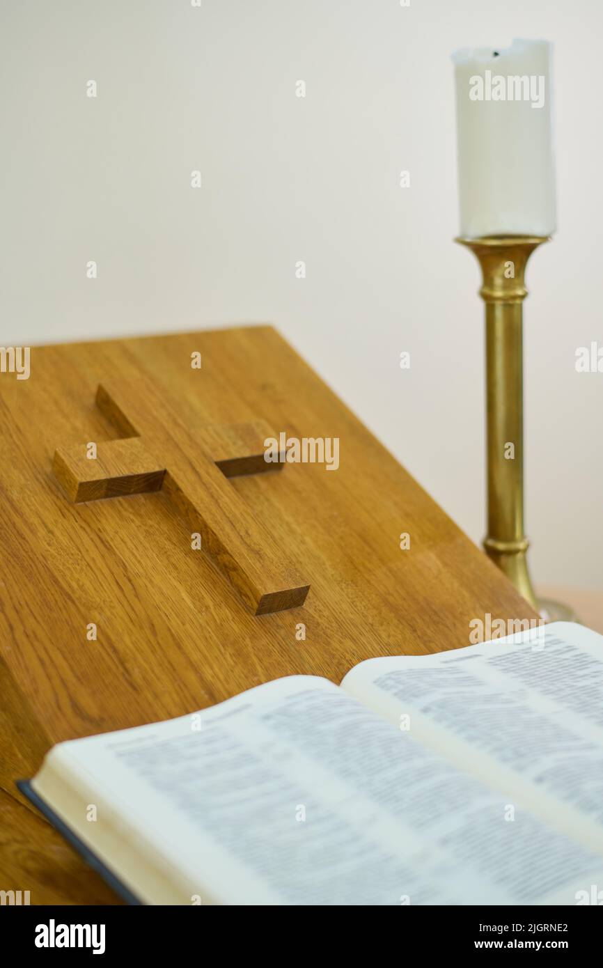 Part of pulpit with cross, burning candle and open Gospel with verses ...