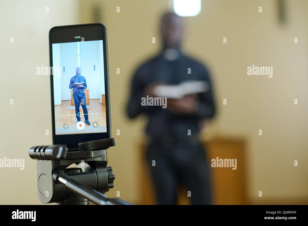 Smartphone with African American pastor in black pants and shirt with ...
