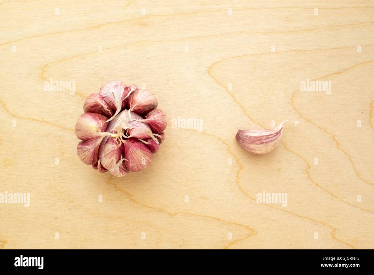 Top view fresh garlic bulb and unpeeled garlic clove on wood desk ...