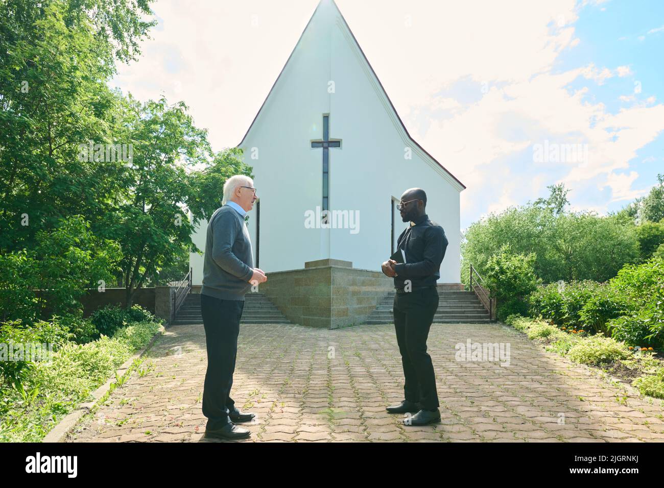 Side view of young pastor and senior male parishioner having discussion ...