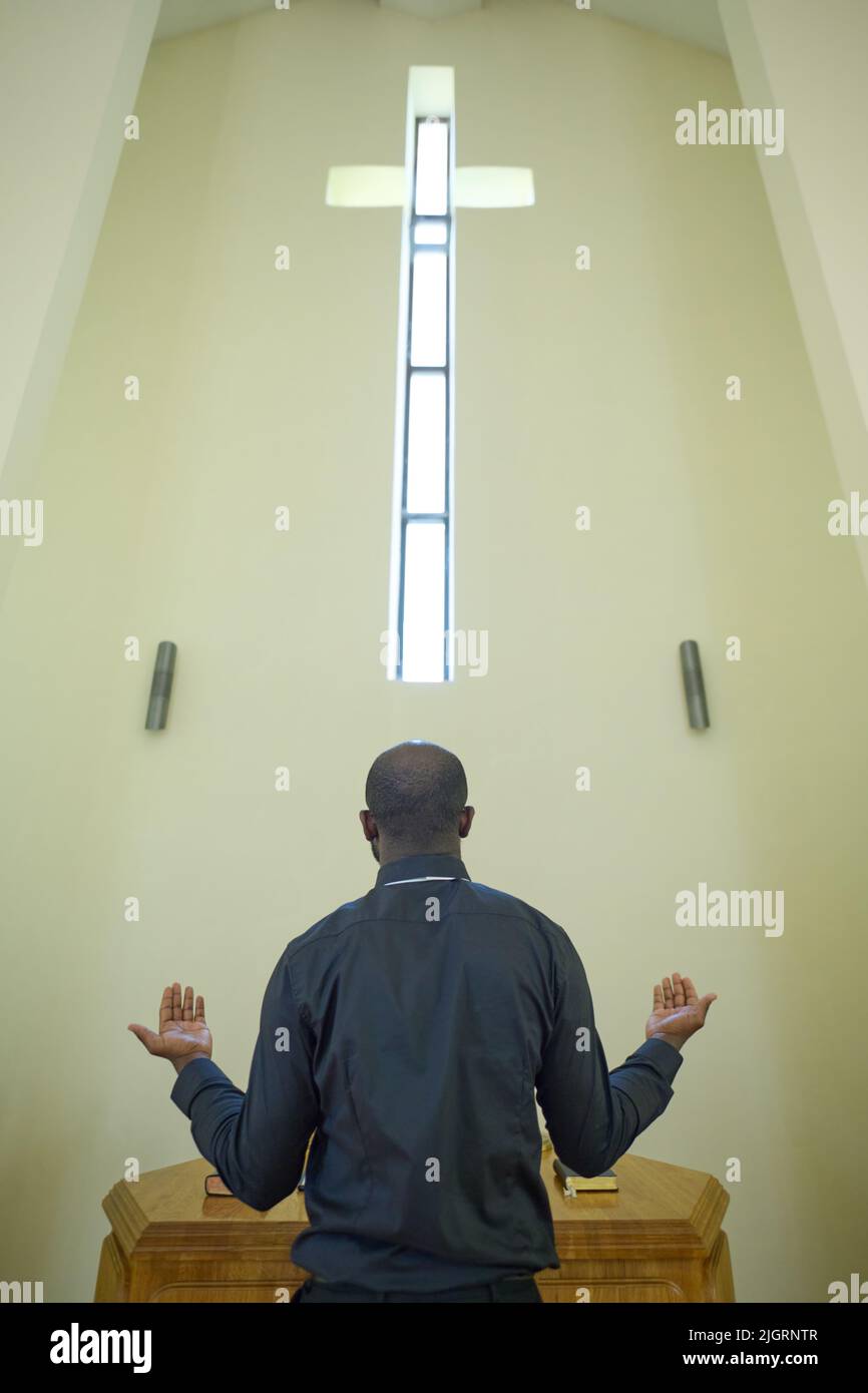 Rear view of young African American pastor in black apparel saying ...