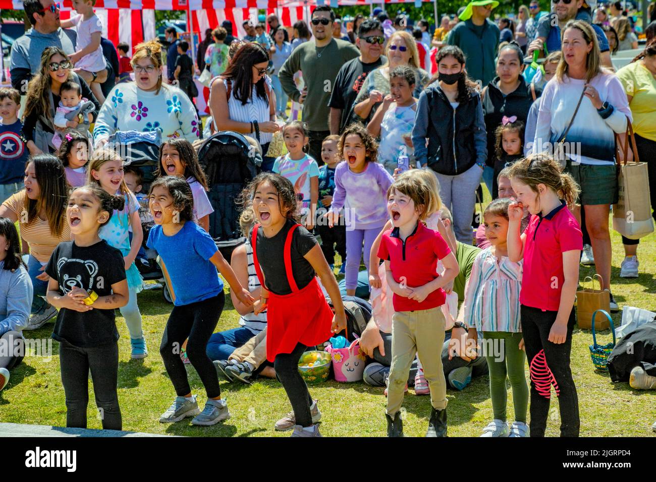 Happy multiracial children sing and dance along to an outdoor ...
