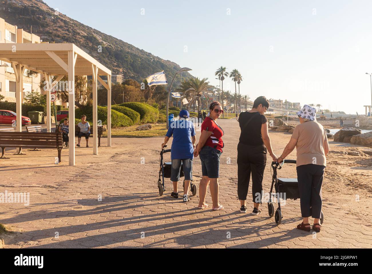 Haifa, Israel - June 20, 2022, Bat Galim beach. Retirees walking along ...